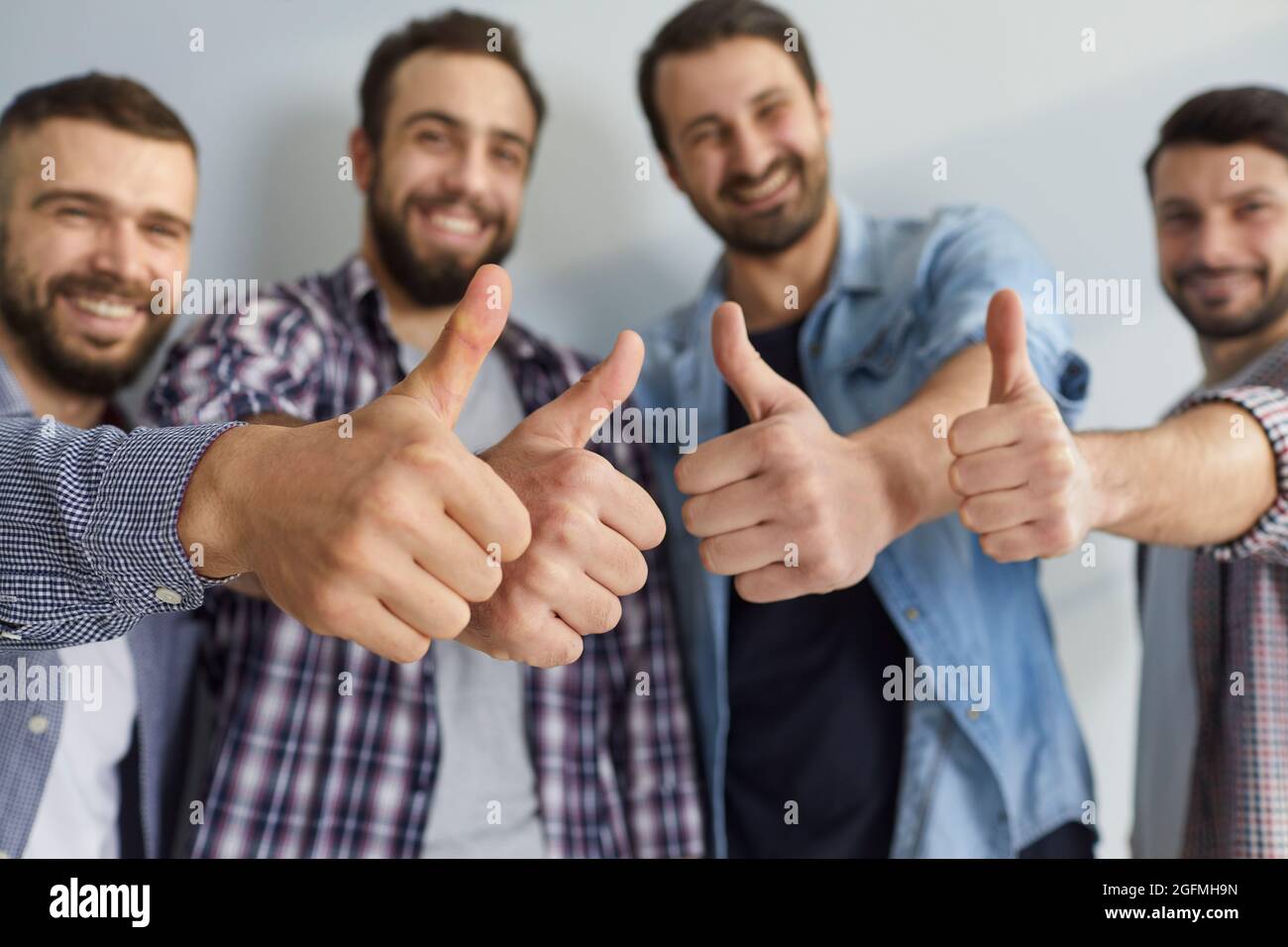 Group of happy positive young men standing together and showing thumbs ...
