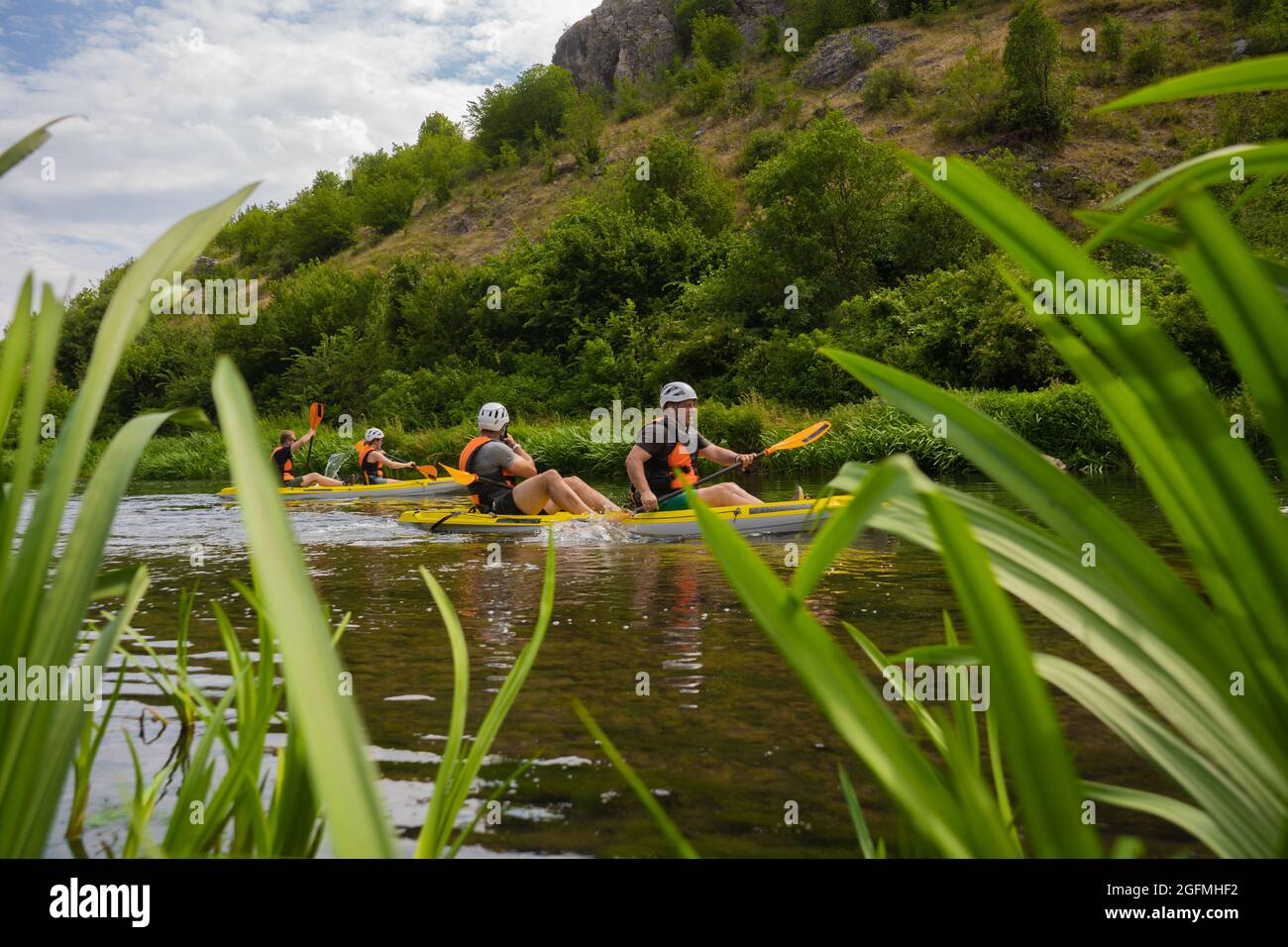 Group of happy friends are kayaking together in pairs while having a ...