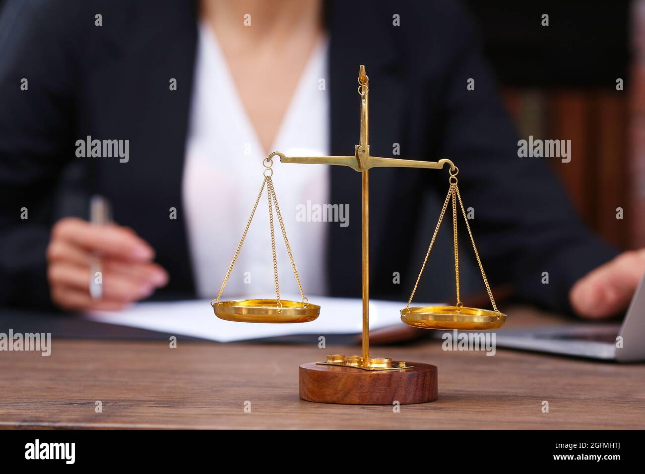 Scales of justice on wooden table and female lawyer on background Stock ...