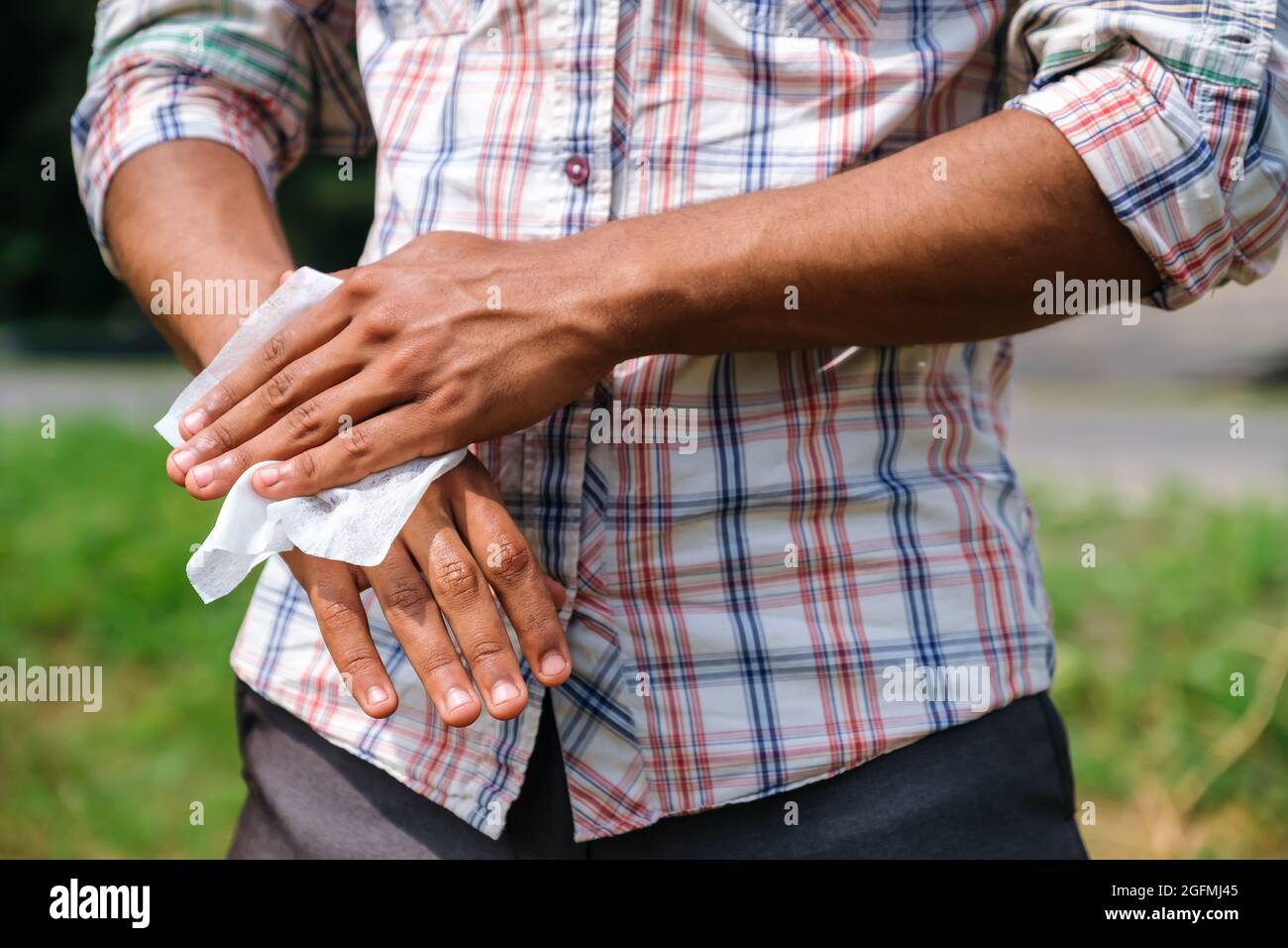 Man disinfecting his hands using wet wipe closeup outdoors to prevent ...
