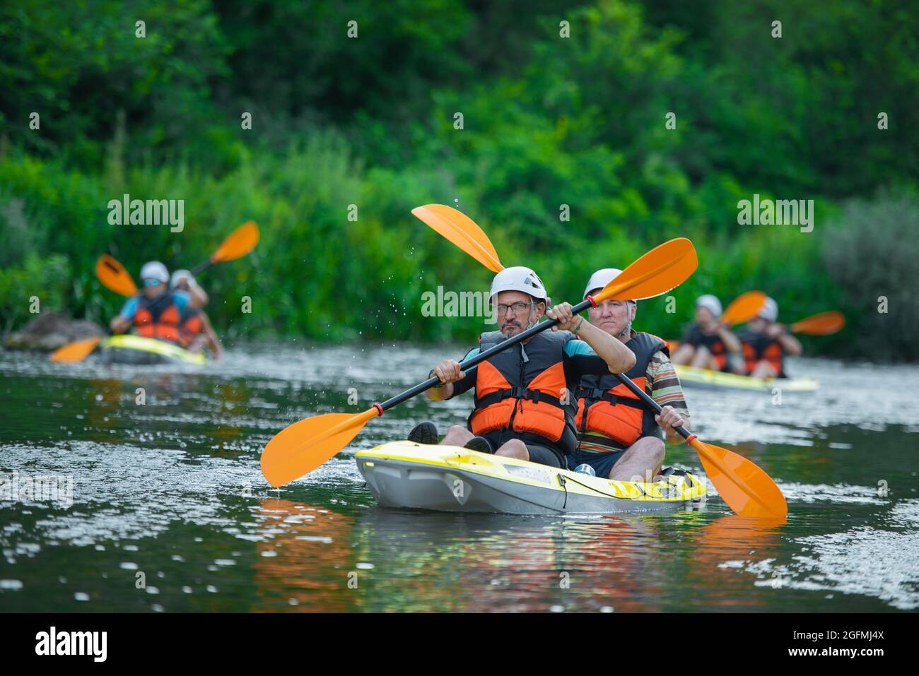 Senior male kayakers are kayaking in pairs together while going all ...