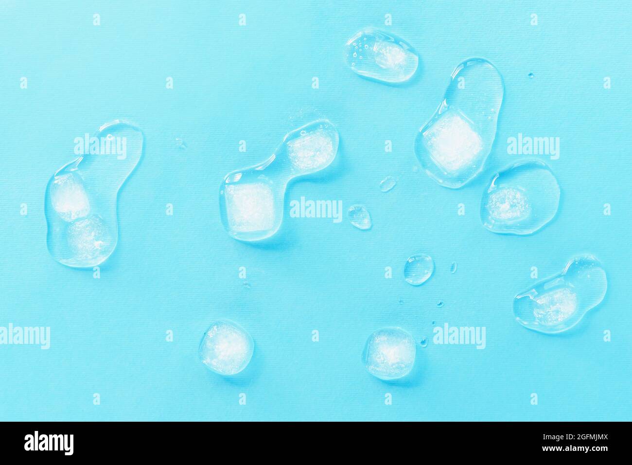 Melting ice cubes scattered on a blue background, top view. Texture ...