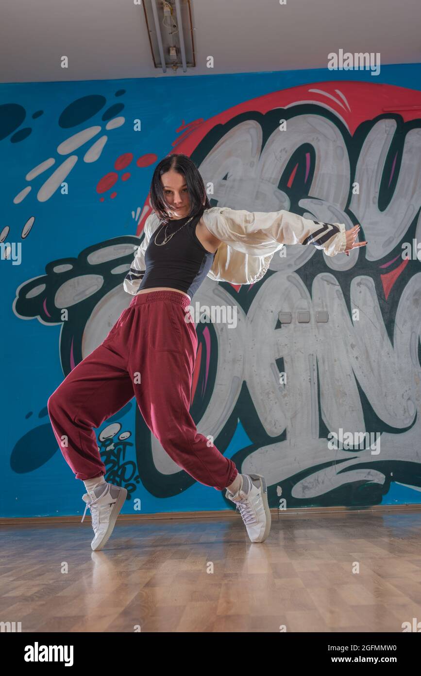 Attractive young woman doing breakdance move over graffiti background ...