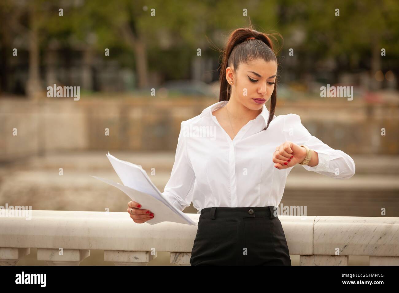 Attractive businesswoman is checking the time while holding the ...