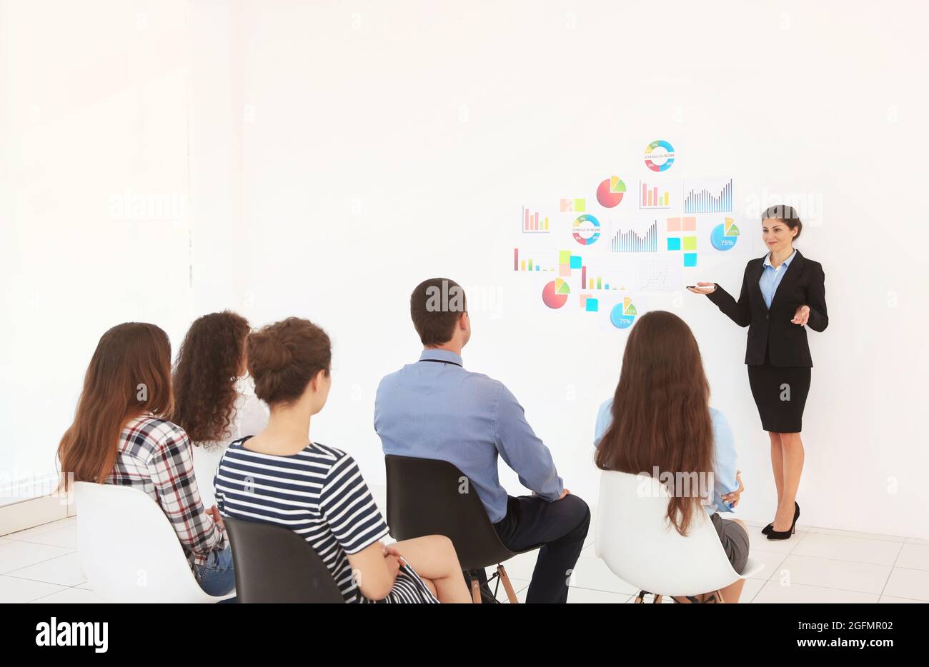 Business trainer giving presentation to group of people Stock Photo - Alamy