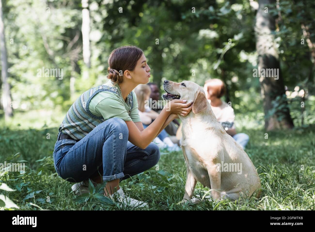 Side view of girl pouting lips while looking at retriever in park Stock ...