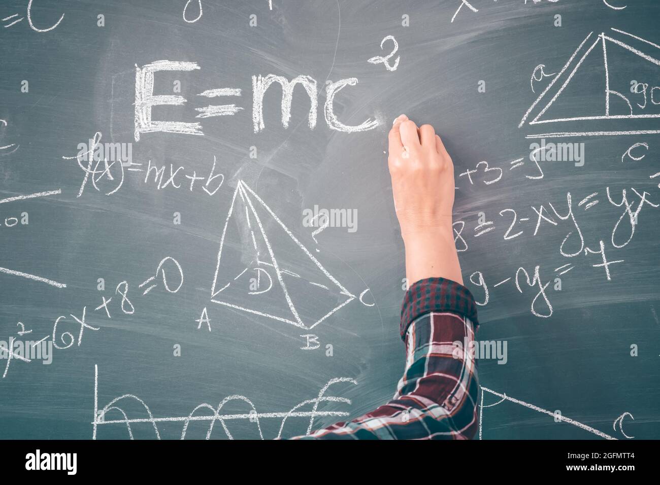 Close-up shot of a hand holding chalk and writing mathematical ...