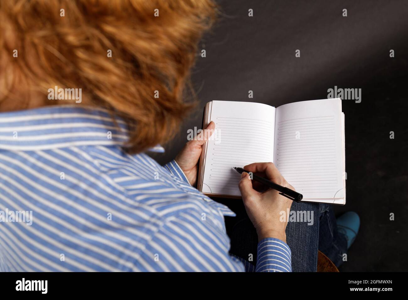 Young woman writes in a white empty diary. A look from behind the ...