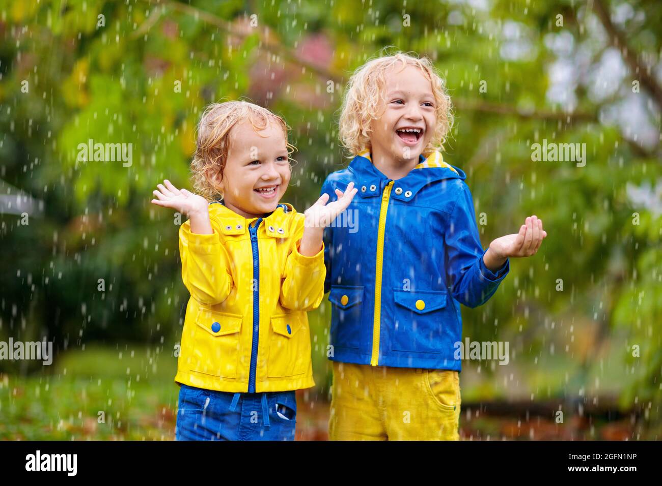 Kids play in autumn rain. Child playing outdoor on rainy day. Little ...