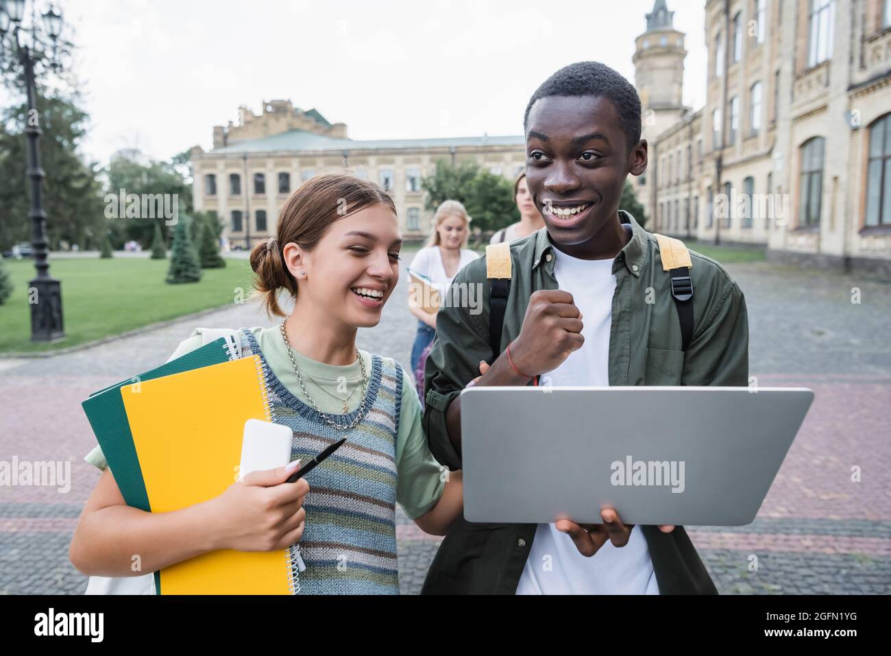 Excited african american student showing yes near friends with ...
