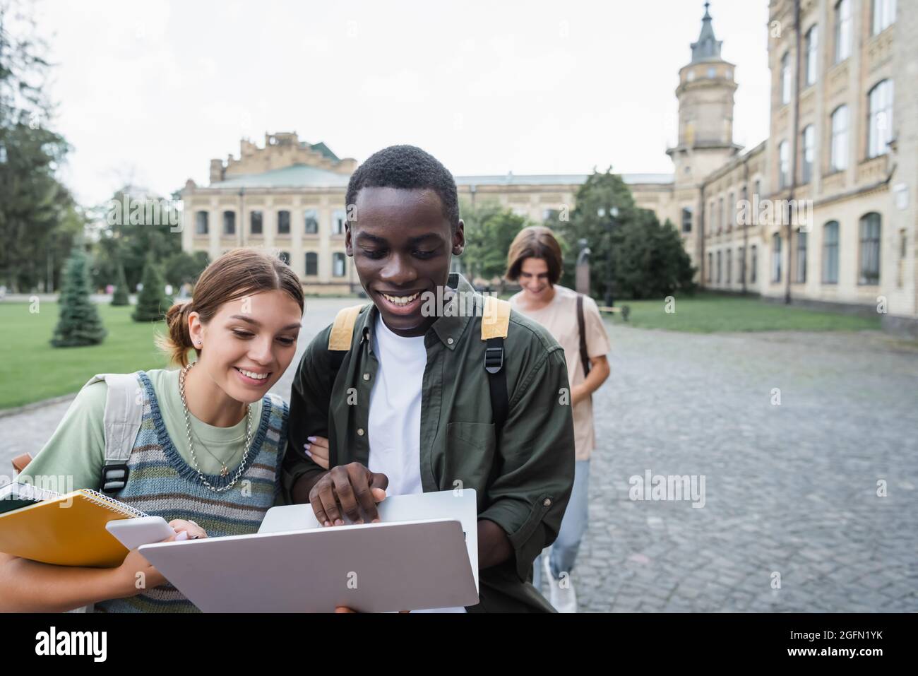 Smiling interracial students using laptop outdoors Stock Photo - Alamy