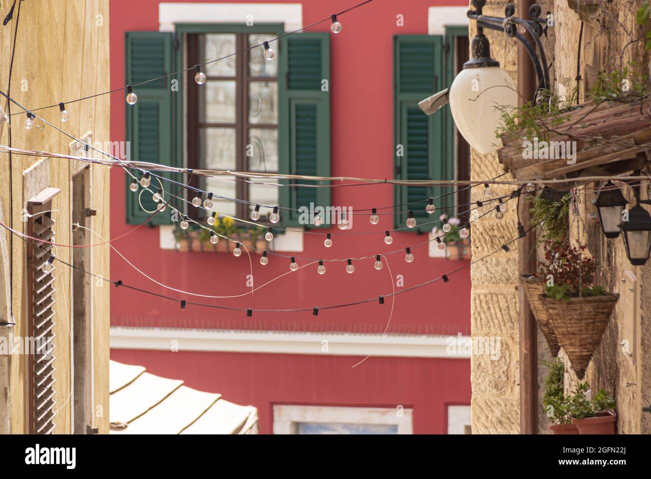 A view of a hanged lights line and home with red wall, green windows in ...