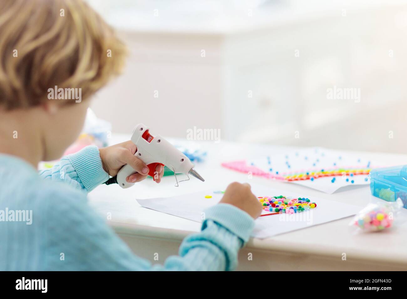 Crafts for kids. Child with hot glue gun. Creative little boy sticking ...