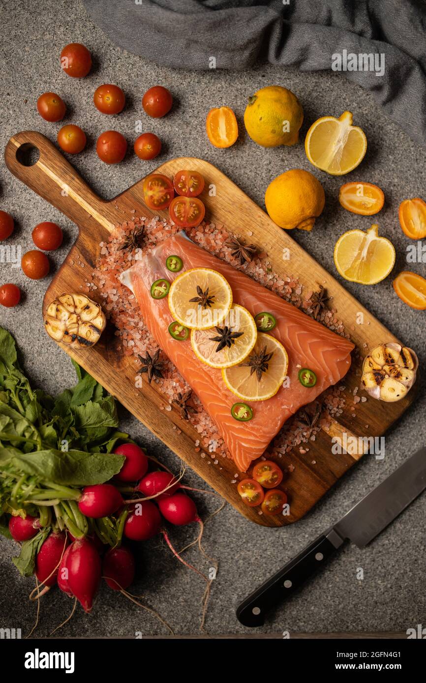 Vertical top view of a raw slice of fish with lemon slices and ...
