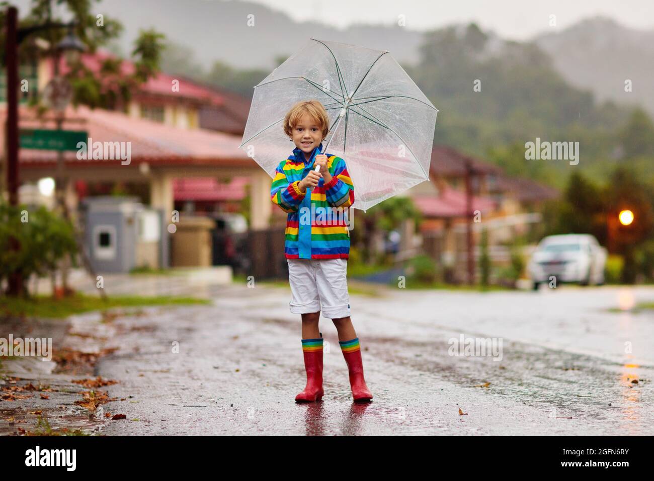 Child playing in autumn rain. Kid with umbrella. Little boy running on ...
