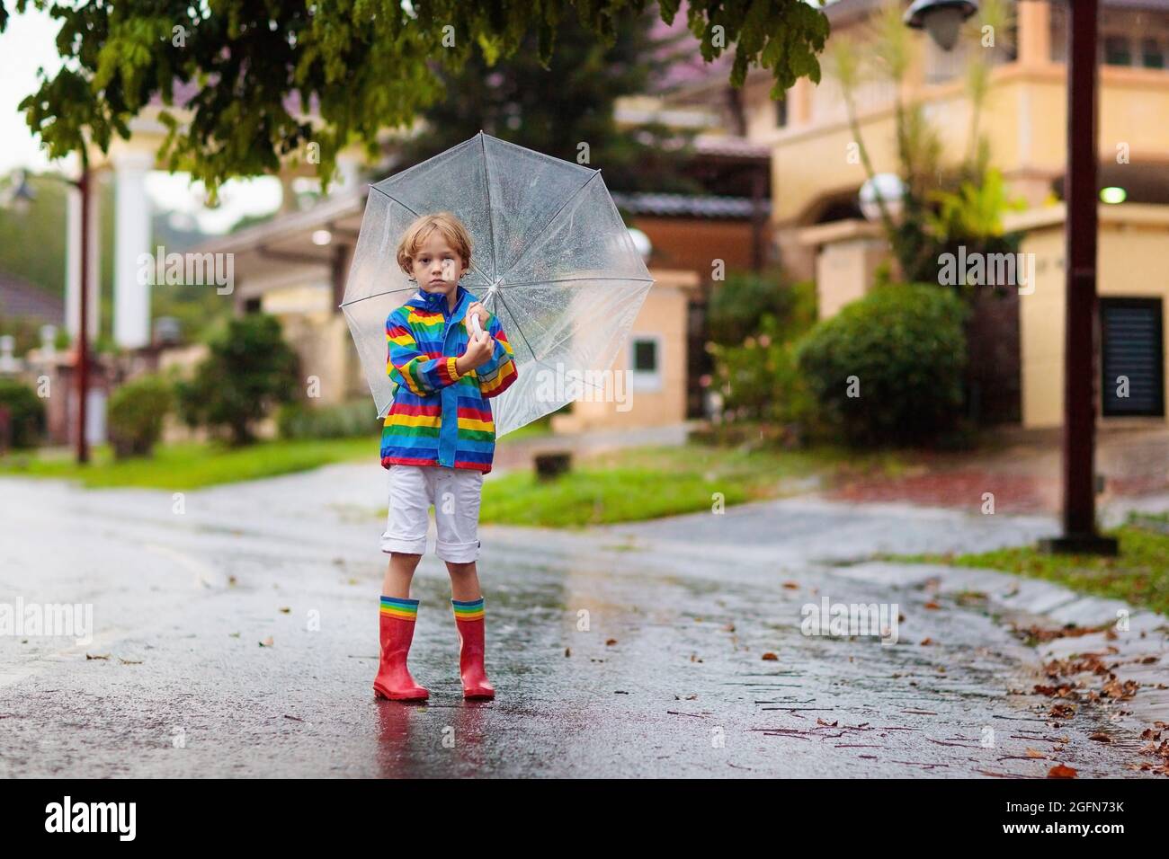 Child playing in autumn rain. Kid with umbrella. Little boy running on ...