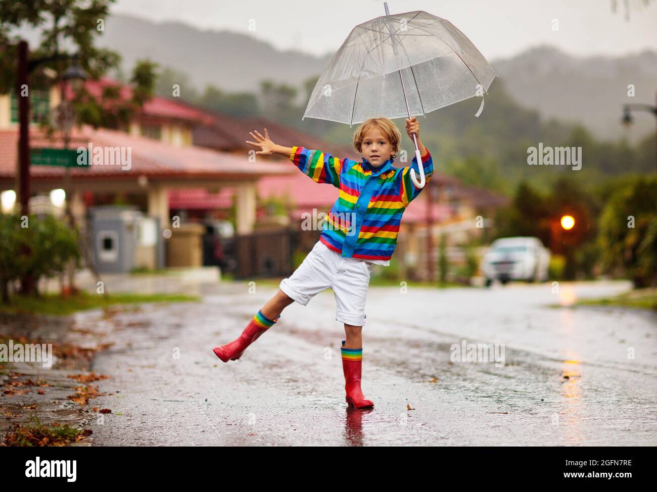 Child playing in autumn rain. Kid with umbrella. Little boy running on ...