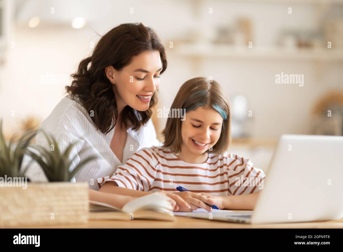 Back to school. Happy child and adult are sitting at desk. Girl doing ...