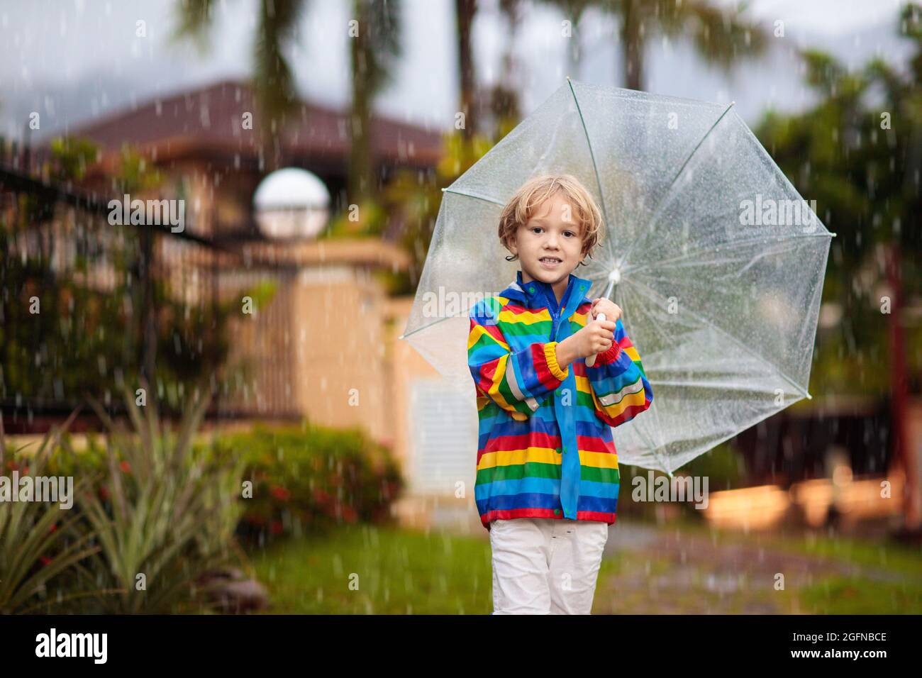Child playing in autumn rain. Kid with umbrella. Little boy running on ...