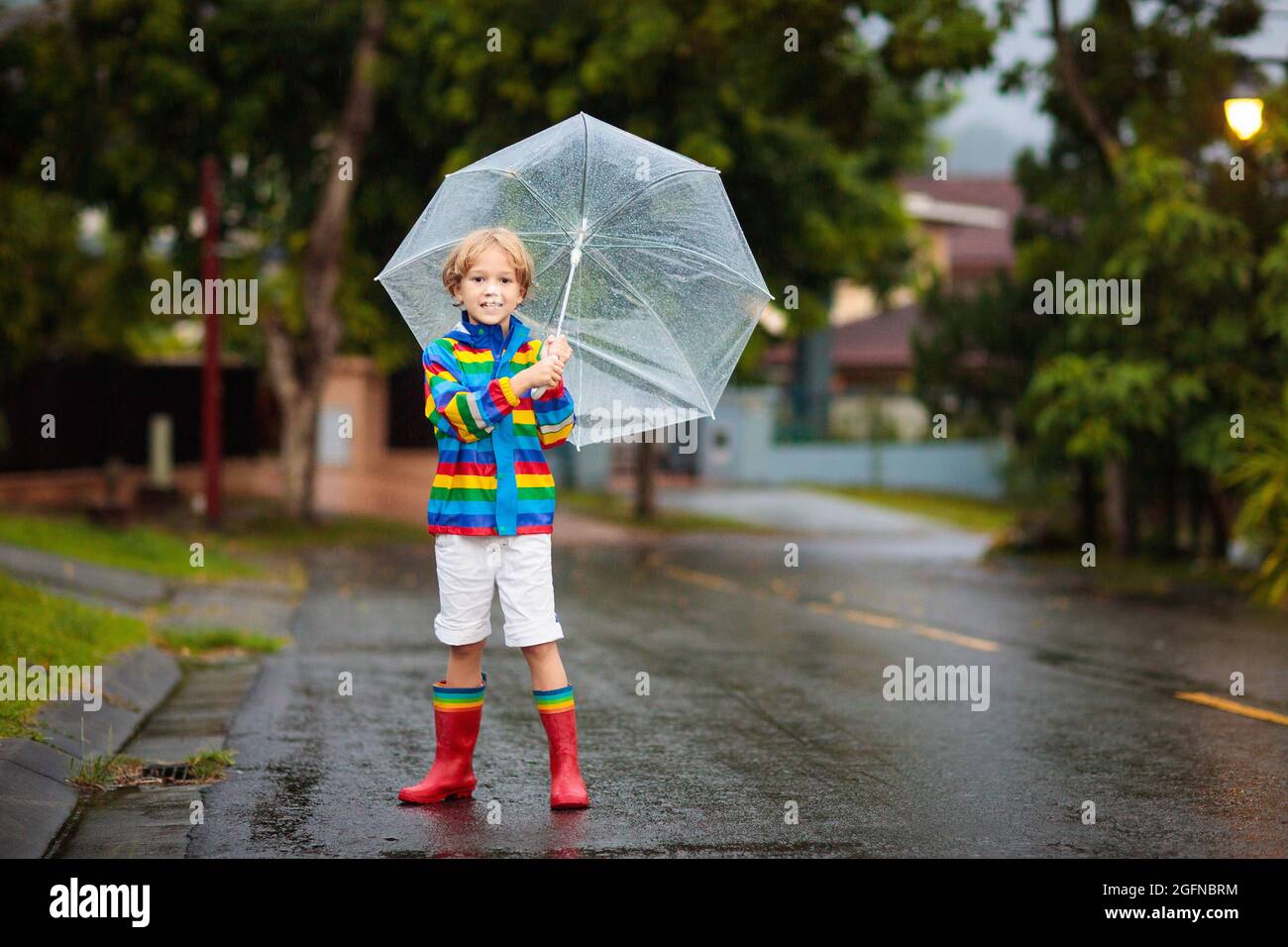 Child playing in autumn rain. Kid with umbrella. Little boy running on ...