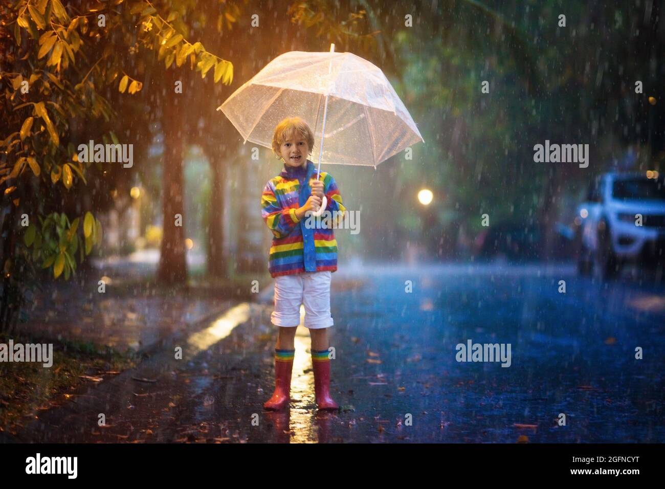 Child playing in autumn rain. Kid with umbrella. Little boy running on ...