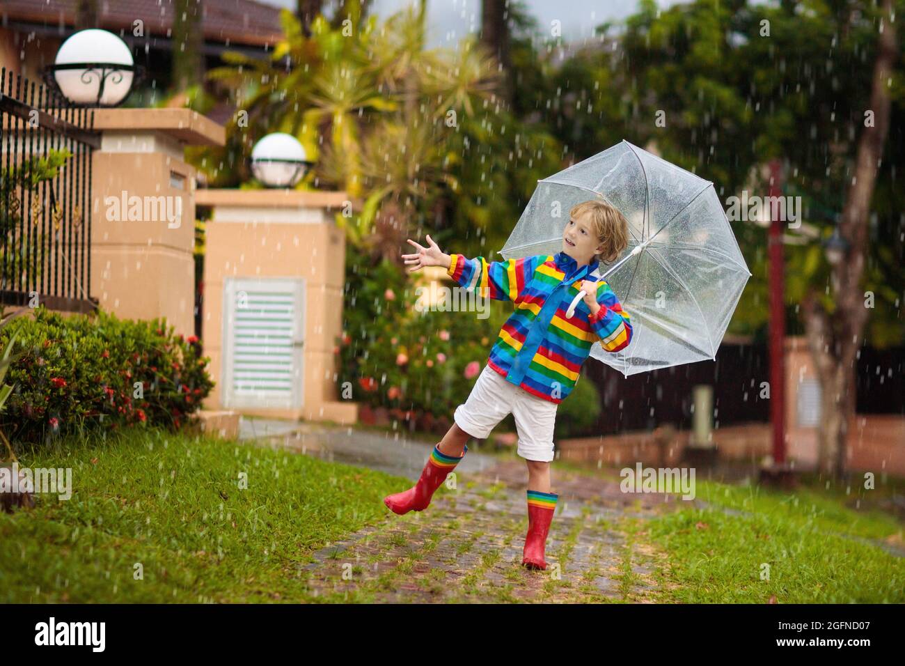 Child playing in autumn rain. Kid with umbrella. Little boy running on ...