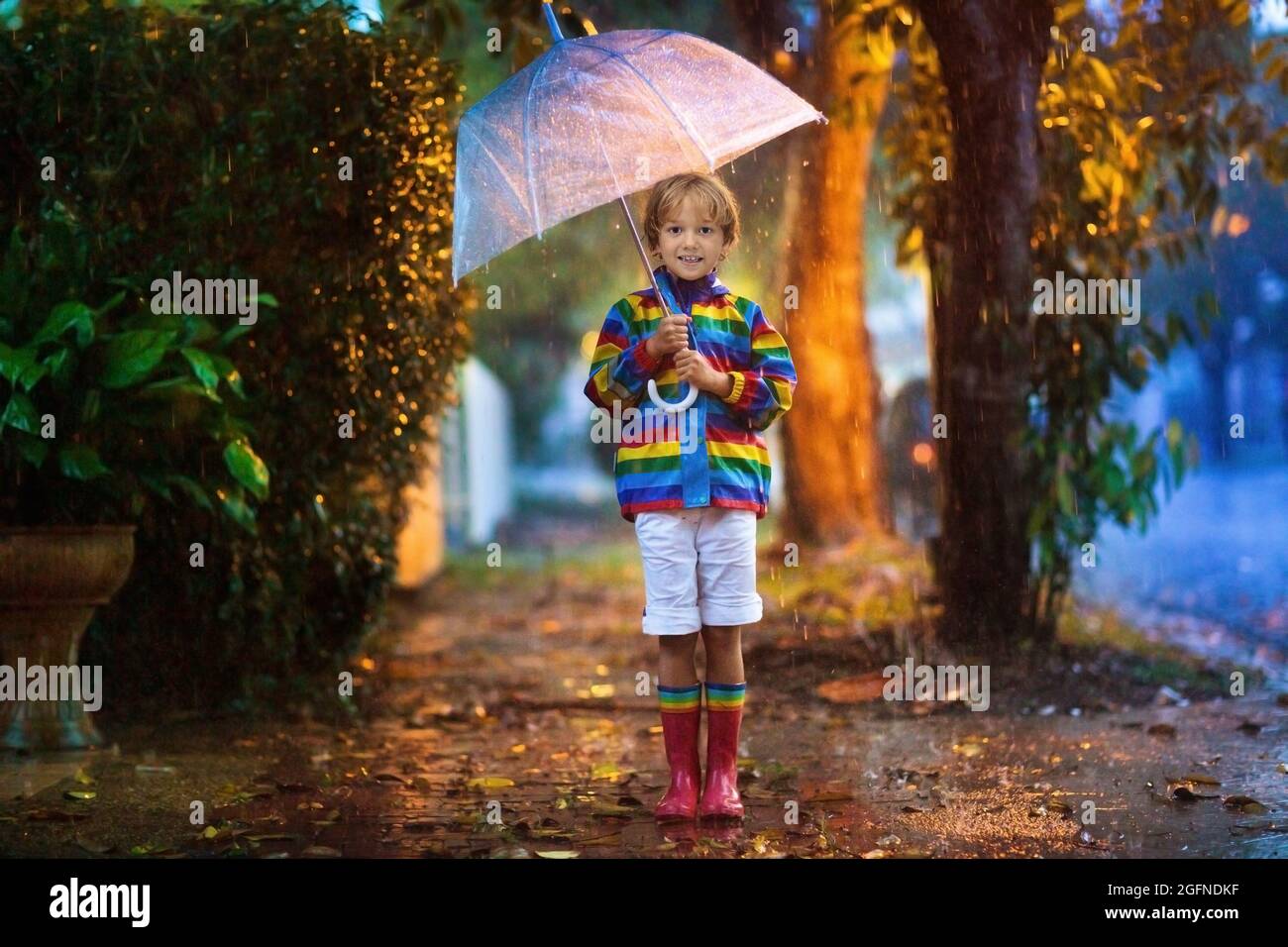 Child playing in autumn rain. Kid with umbrella. Little boy running on ...