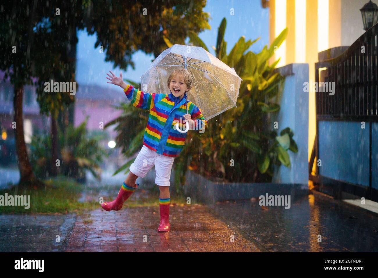 Child playing in autumn rain. Kid with umbrella. Little boy running on ...