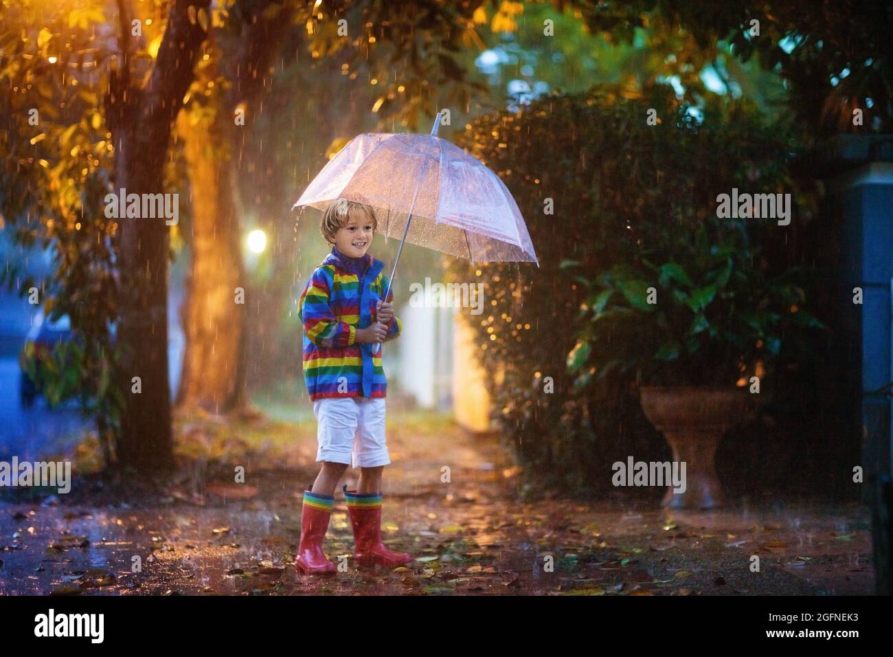 Child playing in autumn rain. Kid with umbrella. Little boy running on ...