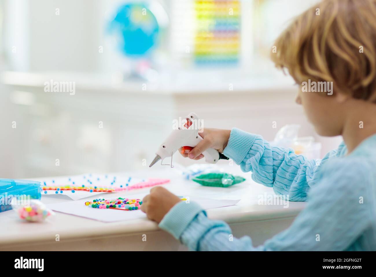 Crafts for kids. Child with hot glue gun. Creative little boy sticking ...