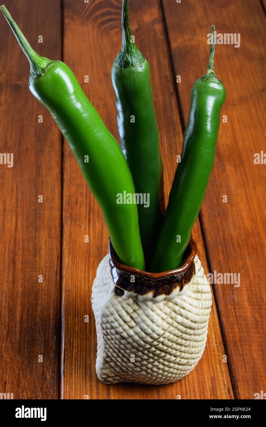 Three green fresh chili pepper pods inserted vertically into a small ...