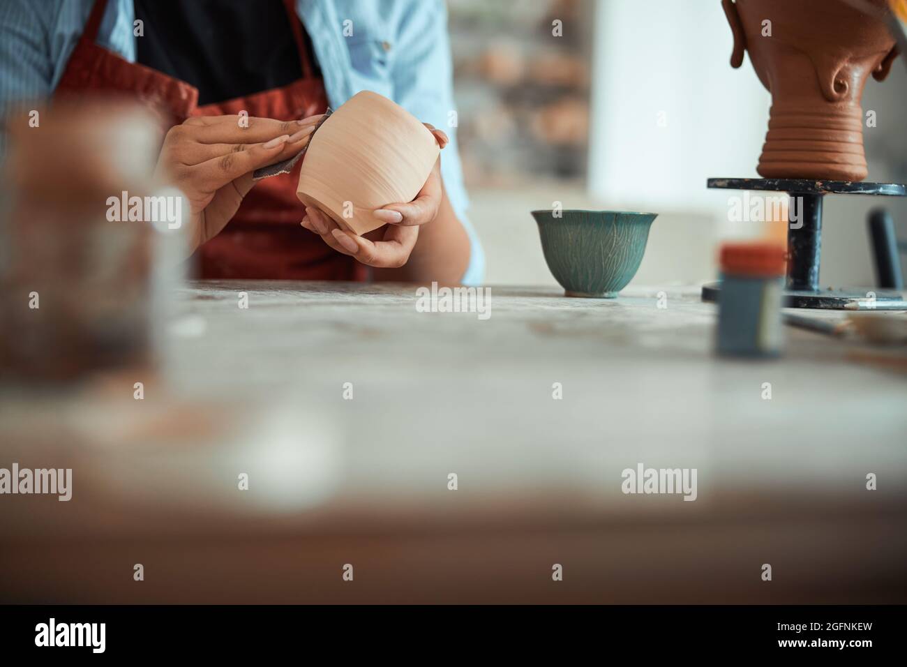 Female ceramic artist polishing clay pot in pottery workshop Stock ...