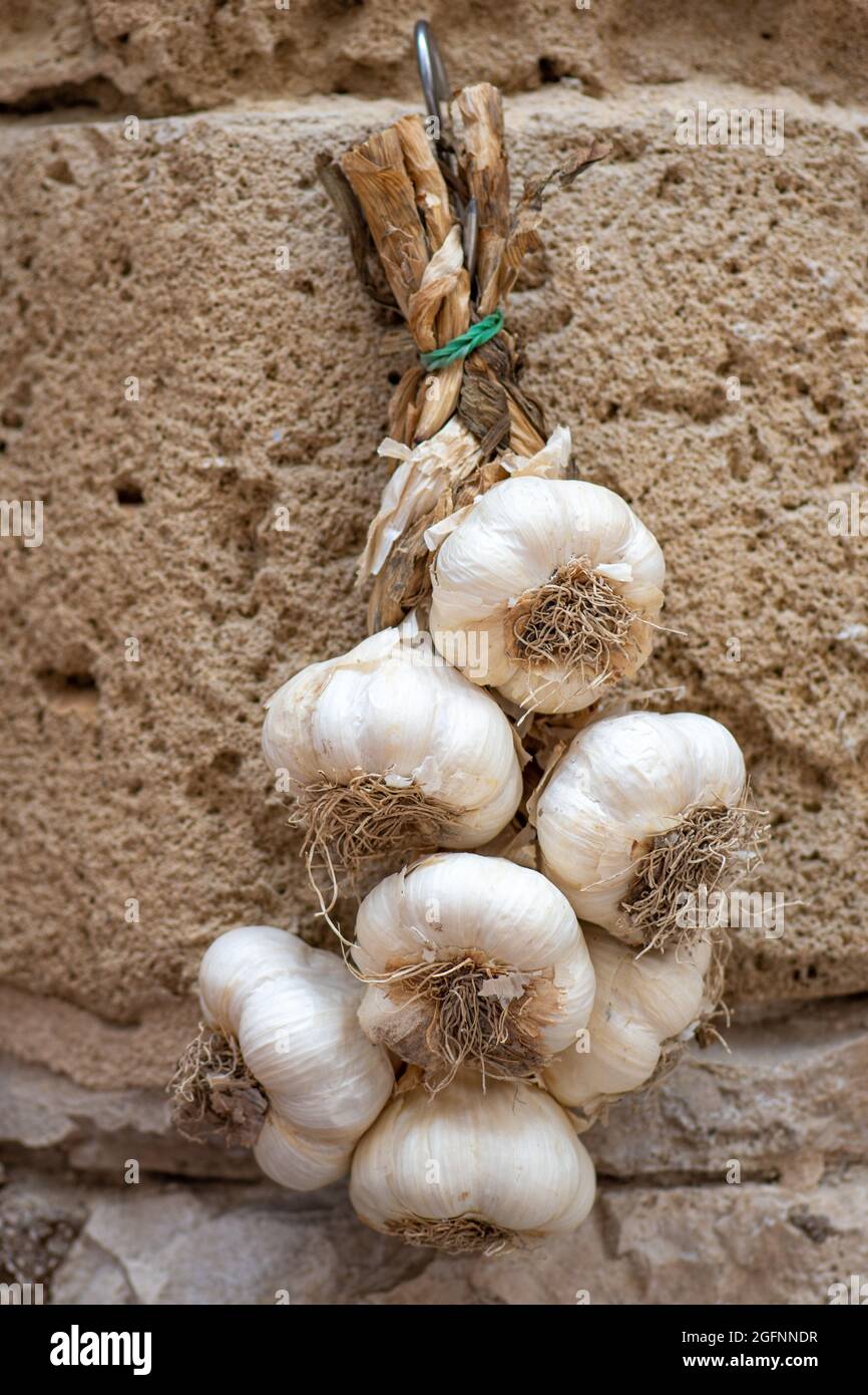Bunch of white garlic hanging on a stone wall in a street food market ...