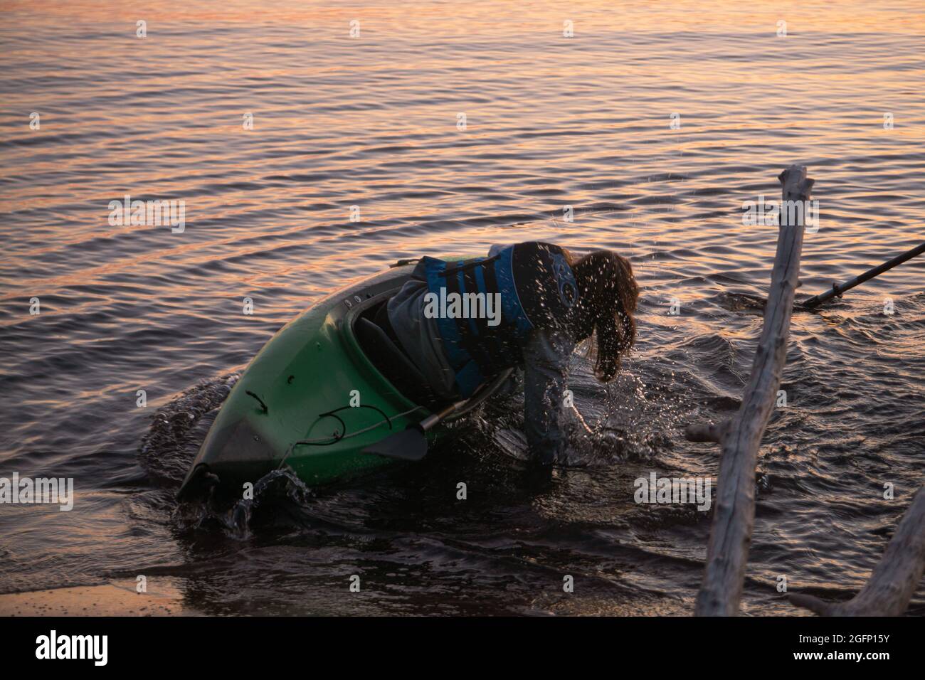 Rear photo of a woman in a kayak struggling to maintain her balance and ...