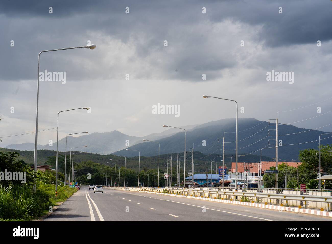Wide asphalt road with streetlights and mountains in the background ...
