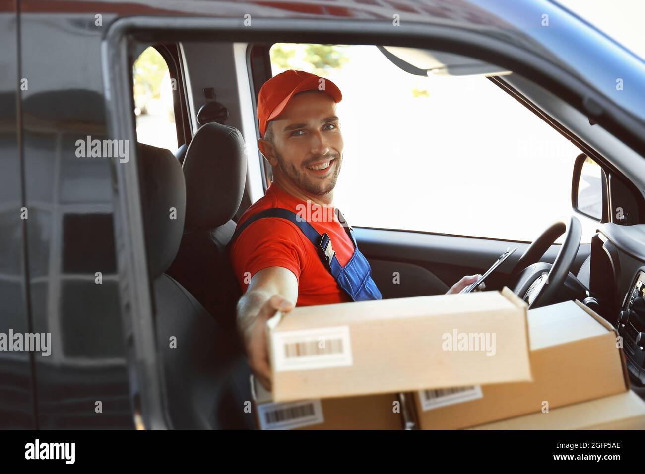 Delivery man with parcels in car Stock Photo - Alamy