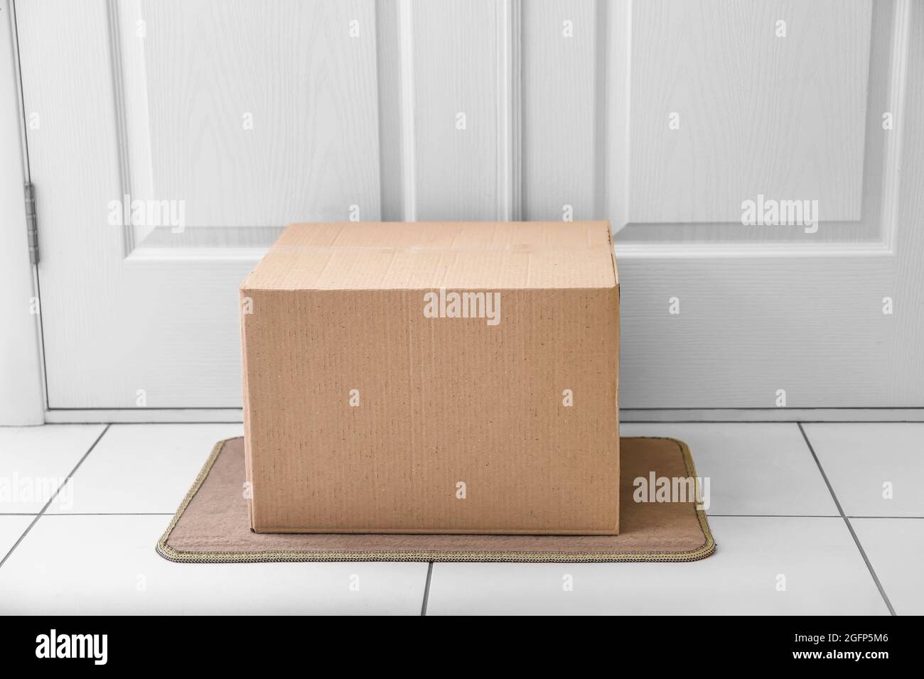 Cardboard box on rug under entrance door Stock Photo - Alamy