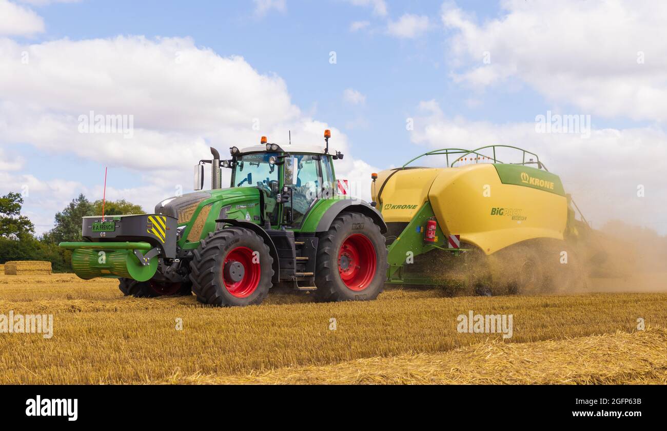 Tractor pulling a baling machine and baling straw in a field ...