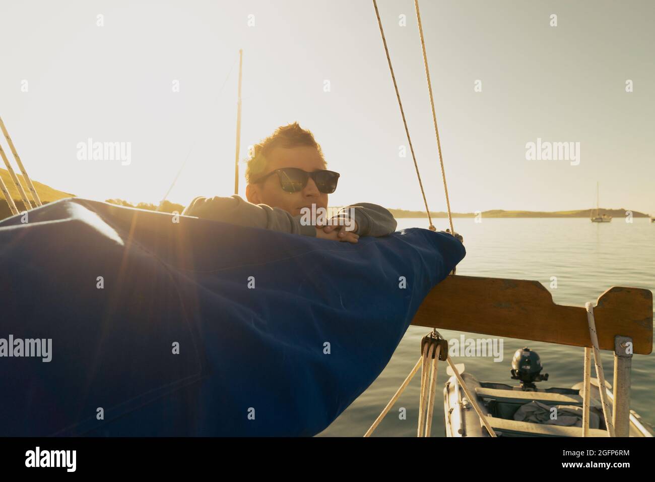 Young man leaning on the boom of a traditional gaff rig sailing boat at ...