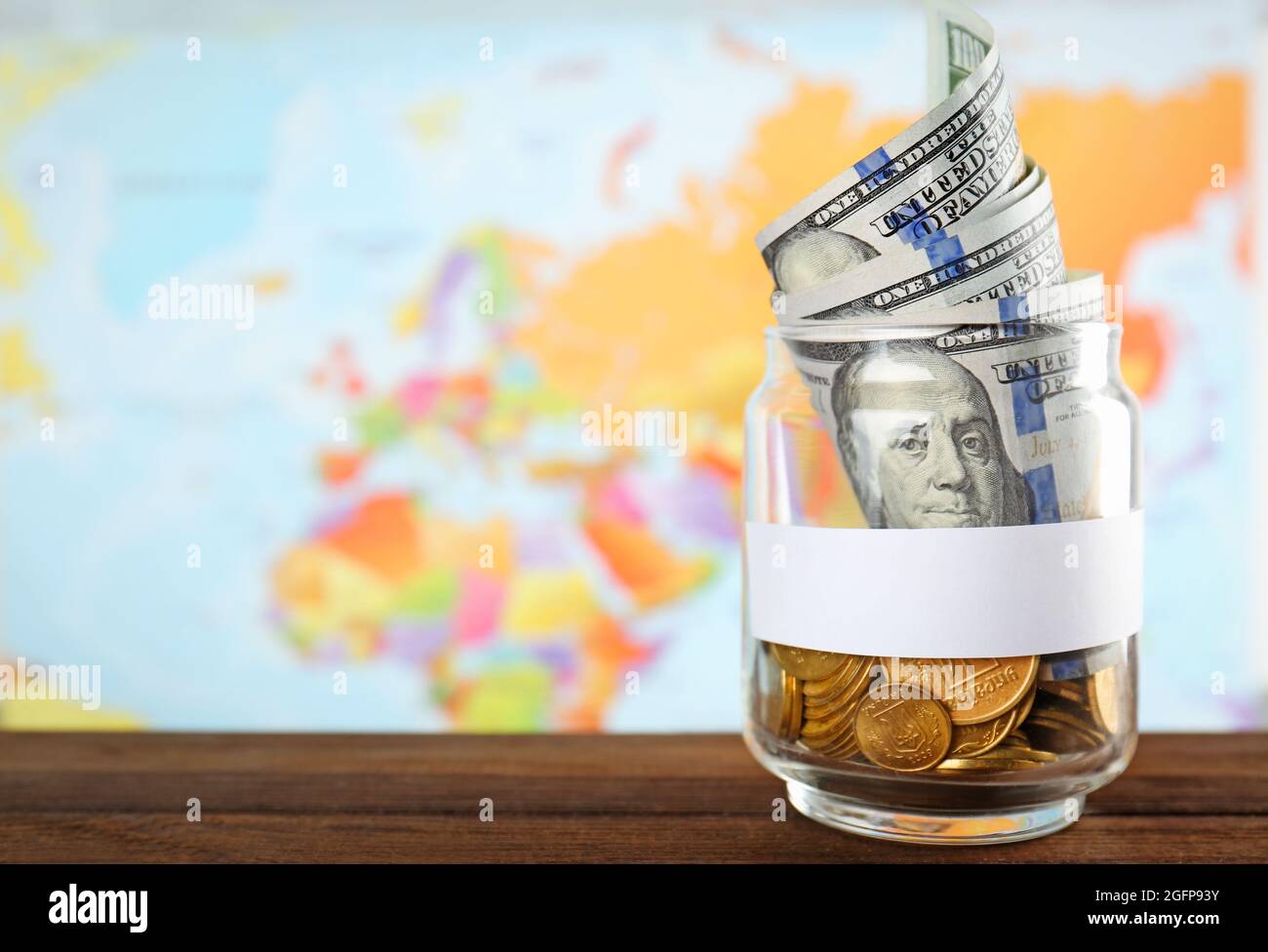 Glass jar with money on world map background Stock Photo - Alamy