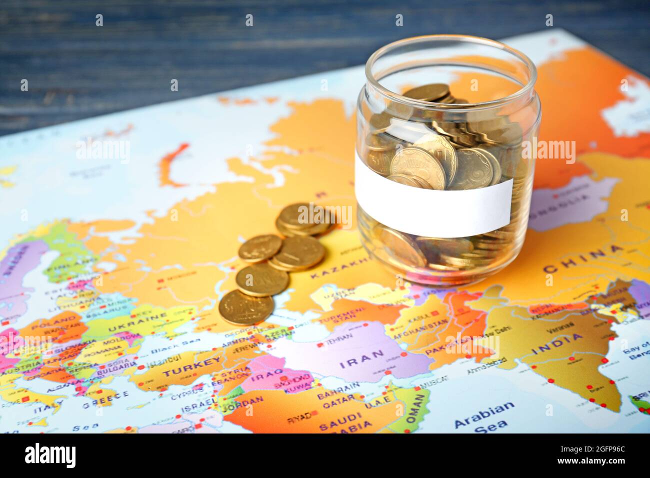 Glass jar with coins on world map Stock Photo - Alamy