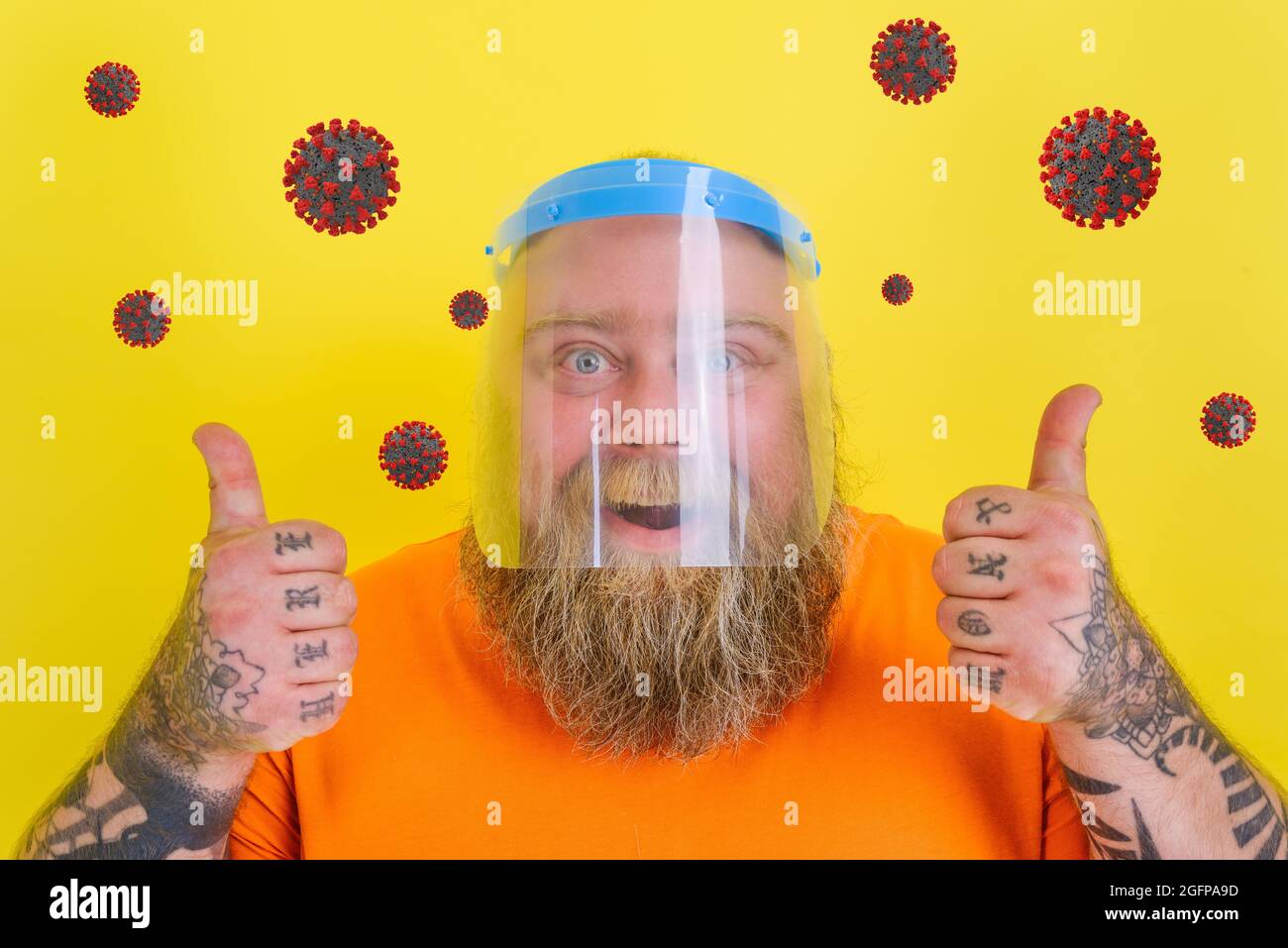 Happy man with beard and tattoos wears a protective face shield against ...