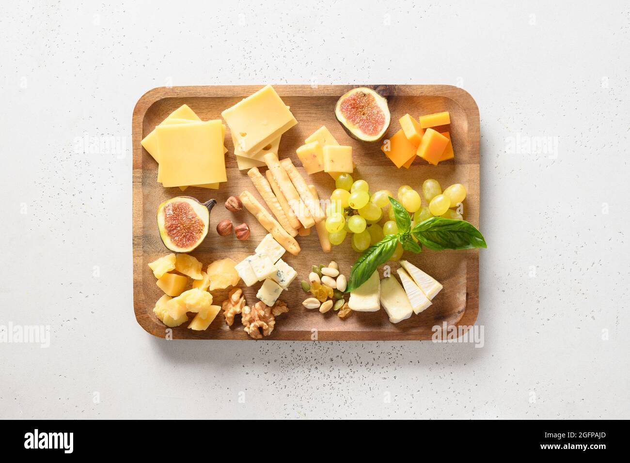 Cheese platter with grapes, nuts, figs on a white background. View from ...