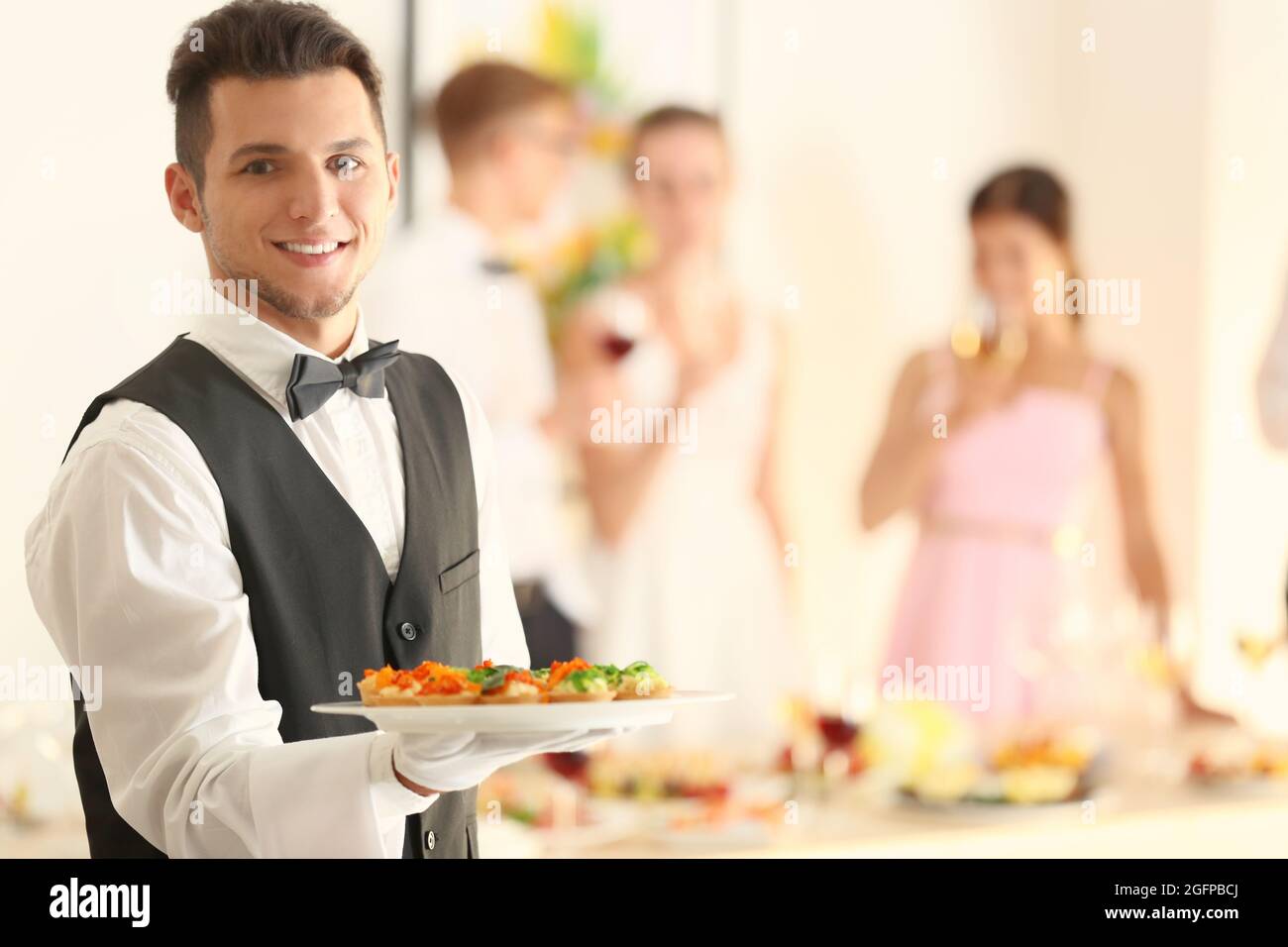 Handsome young waiter with plate full of tasty tartlets at party Stock ...