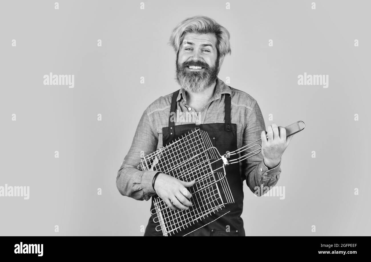 Tools for roasting meat. Man in apron hold barbecue grill. Chef cooking ...