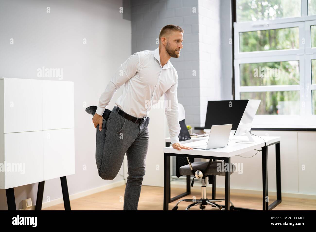 Yoga Workout In Office Behind Business Computer. Gymnastics And Leg ...