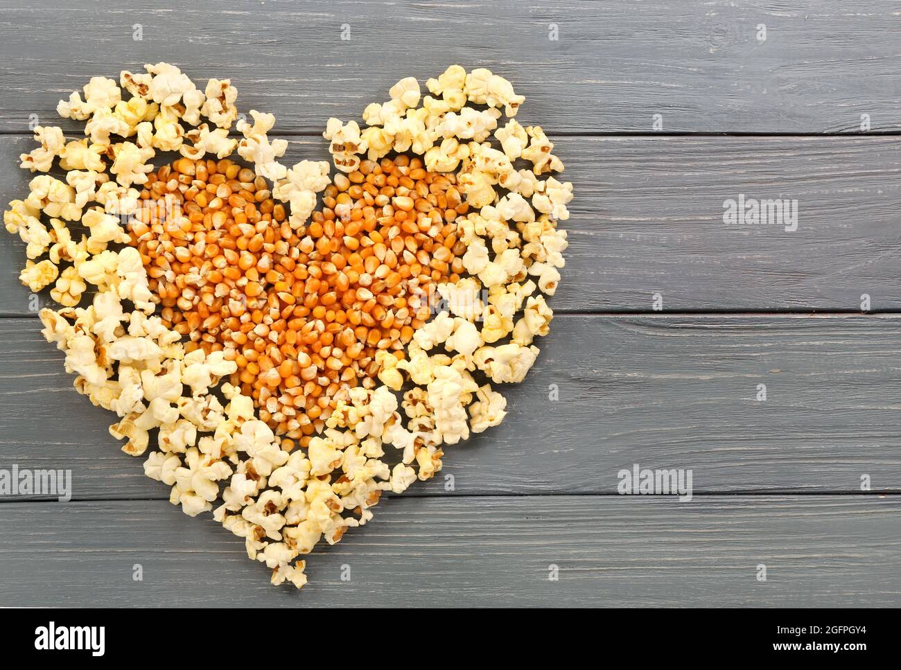 Heart made of popcorn and maize grains on wooden background, top view ...