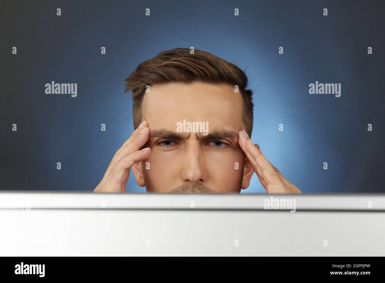 Thinking man sitting at computer monitor on dark background Stock Photo ...