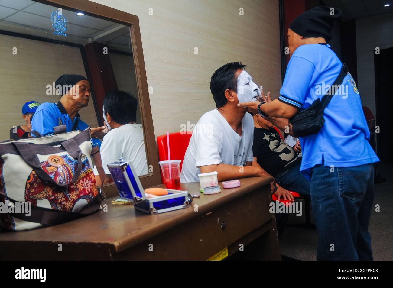 A make-up artist is putting on makeup for a puppet actor or pemain ...