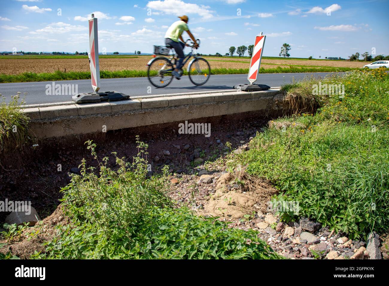 Country road with a broken embankment, flood damage, bicycle in motion ...